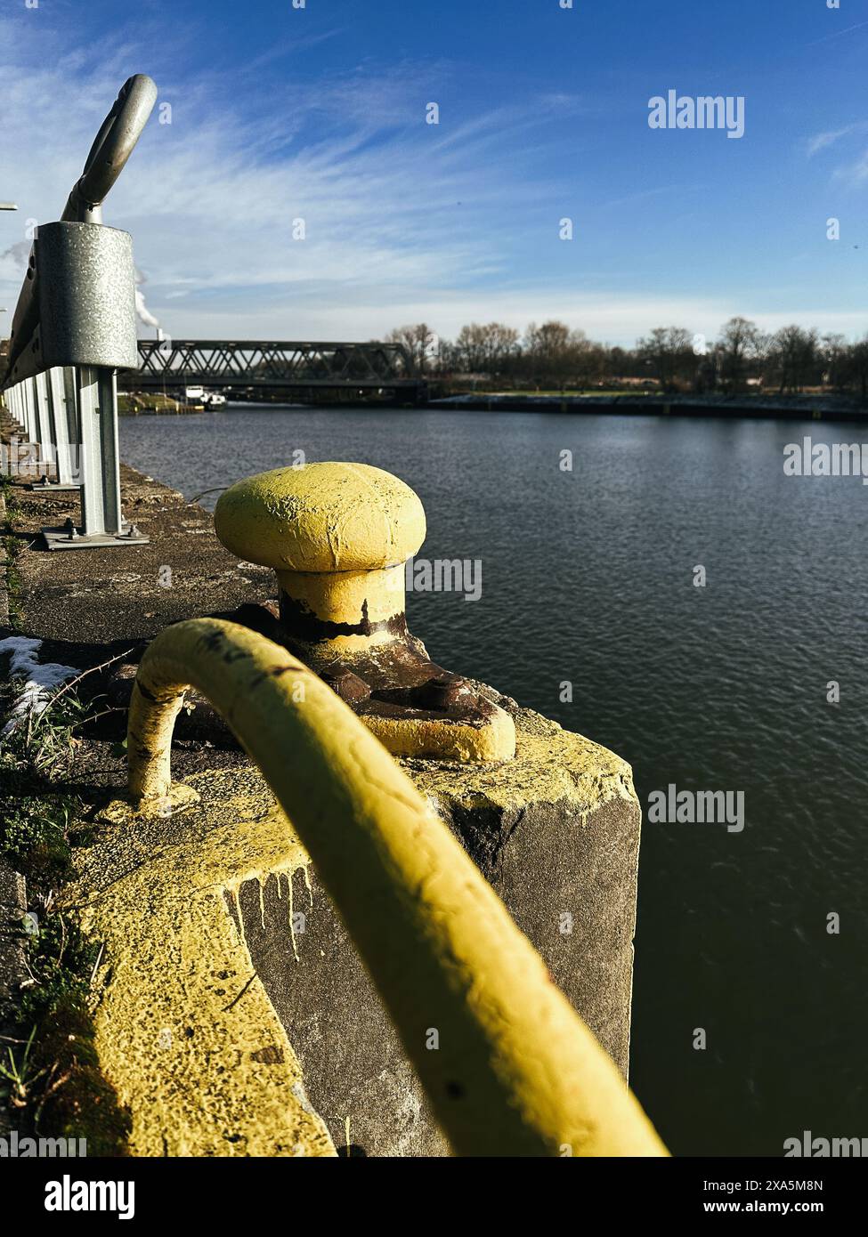 A metal railing by river with trees and grass, yellow color Stock Photo ...