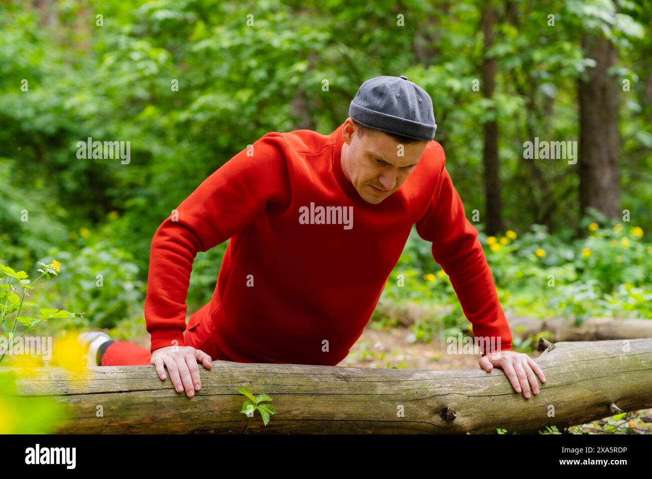 A man performs push-ups using the log as support. The backdrop is a ...