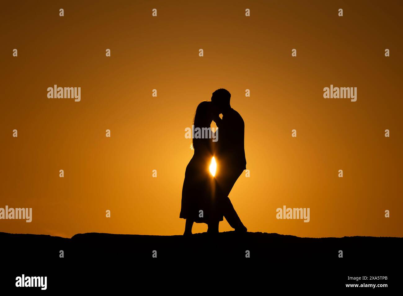 A couple is kissing in the sun, with the sun shining on them Stock ...