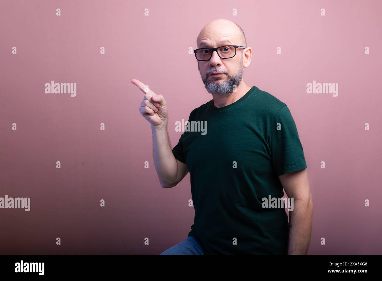 Bearded Bald Man With Prescription Glasses Pointing With His Finger To