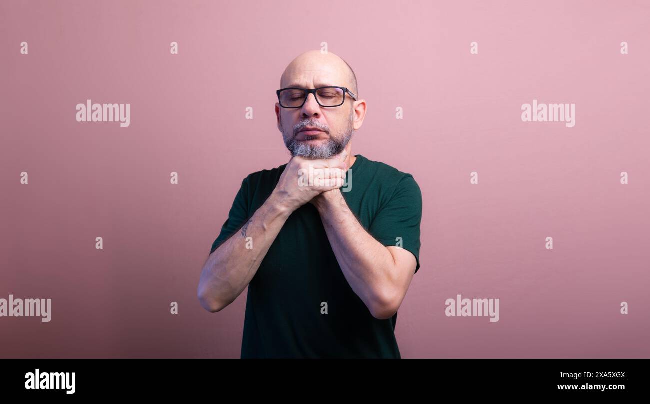 Bearded Bald Man With Prescription Glasses Squeezing His Neck With Both