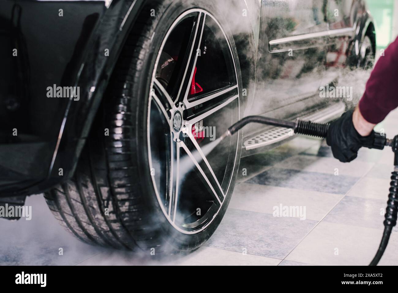 A person washing a car with a high-pressure sprayer in a garage Stock ...