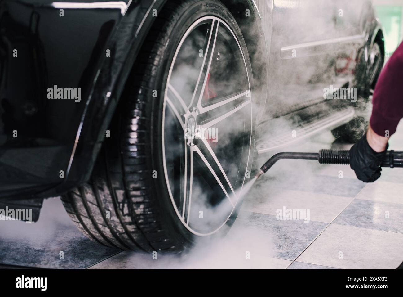 A person washing a car with a high-pressure sprayer in a garage Stock ...