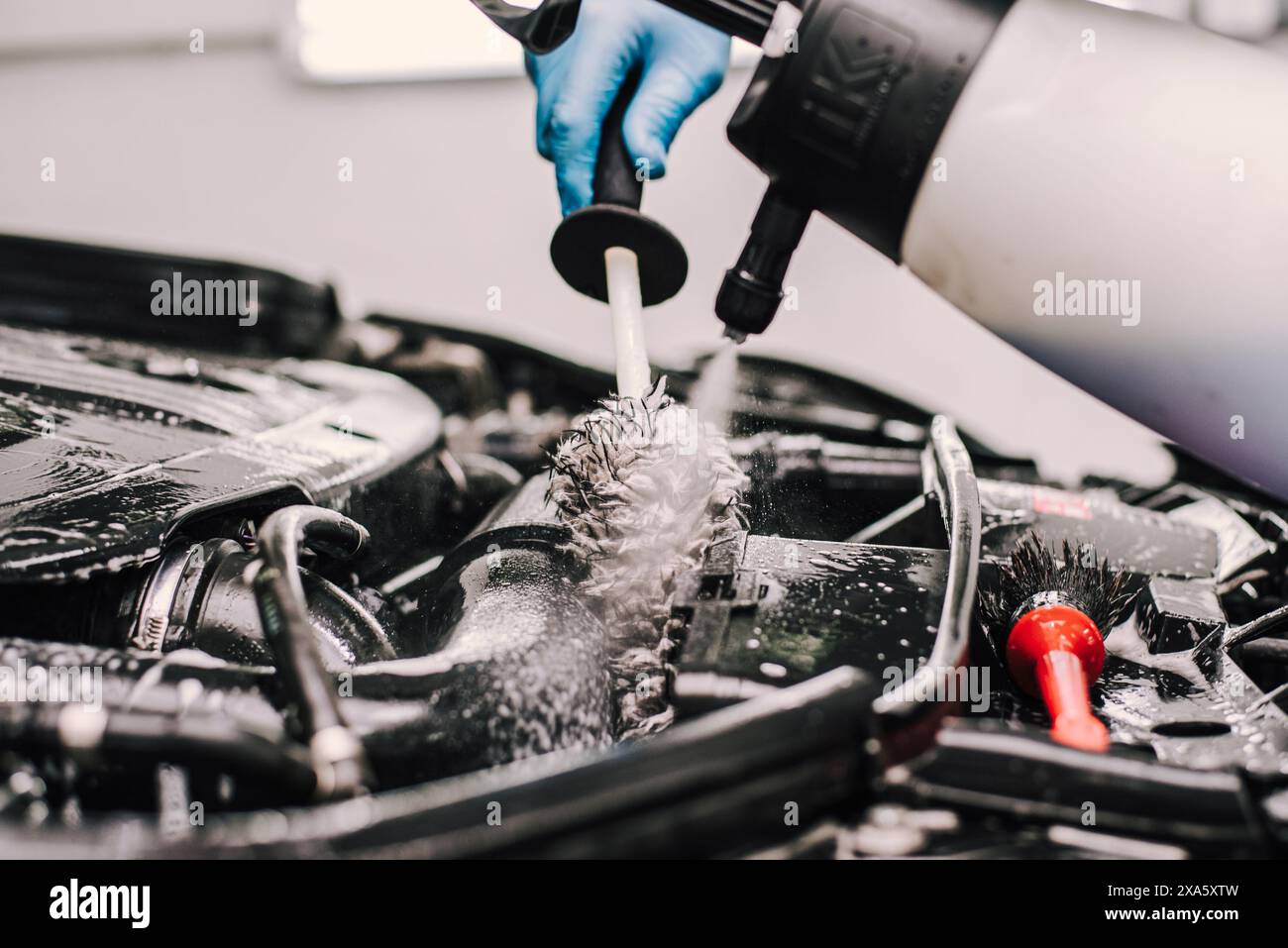 A person wearing gloves cleaning the car engine and interior parts ...