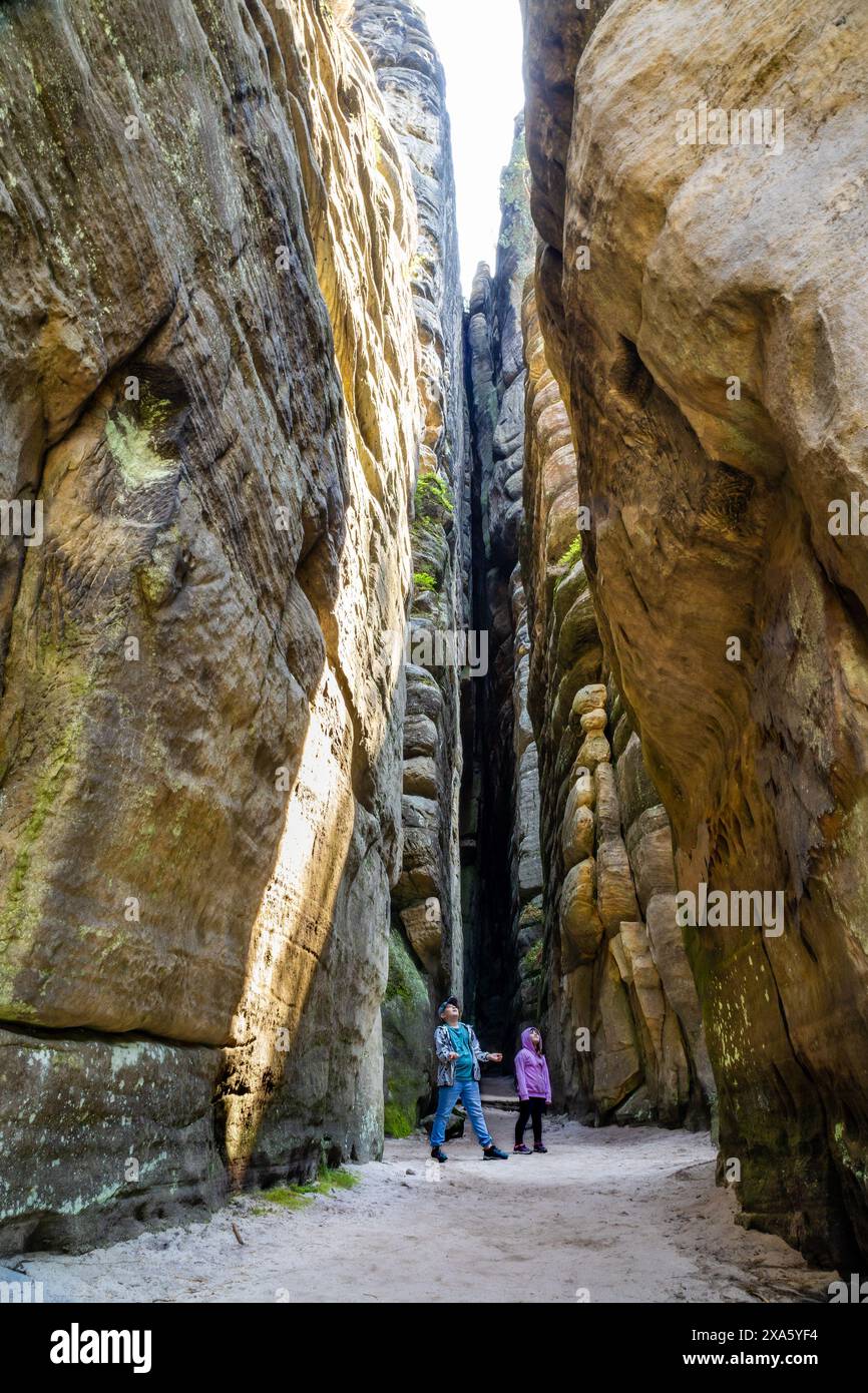 Children stand between high rocks. A gap between high rocks Stock Photo ...