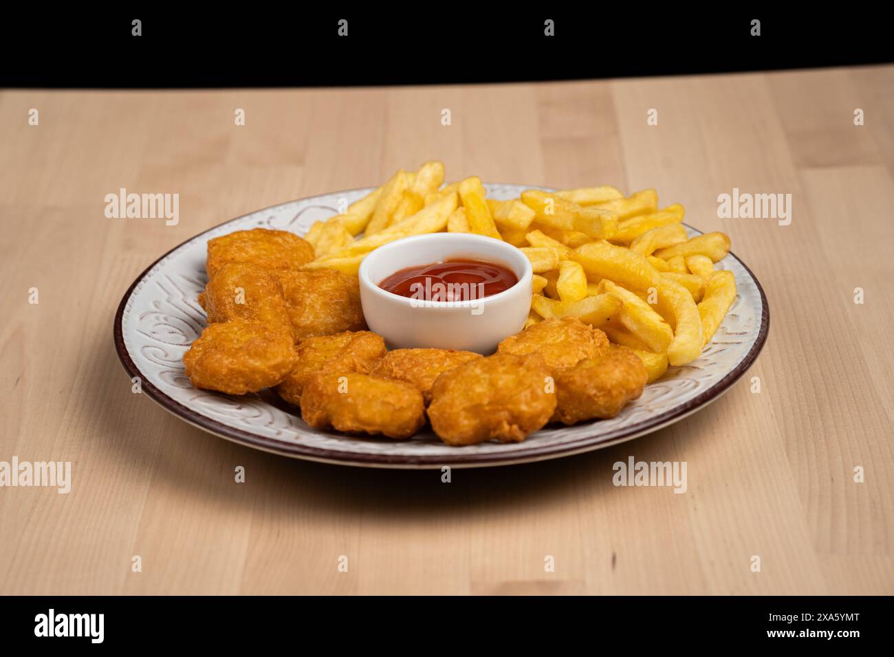 A close-up of delicious fried chicken nuggets and crispy fries served ...