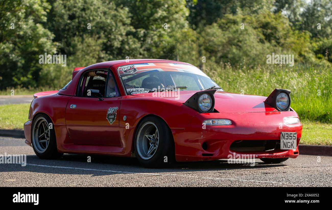 Stony Stratford,UK - June 2nd 2024: 1996 red Mazda MX-5 with pop up headlights car driving on a ...