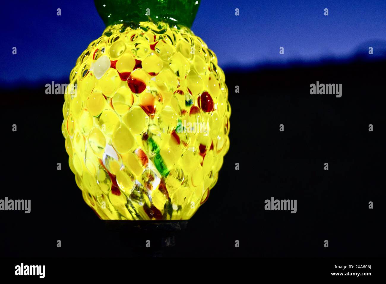 A close up of a pretty yellow Solar Light in a yard at night glowing ...