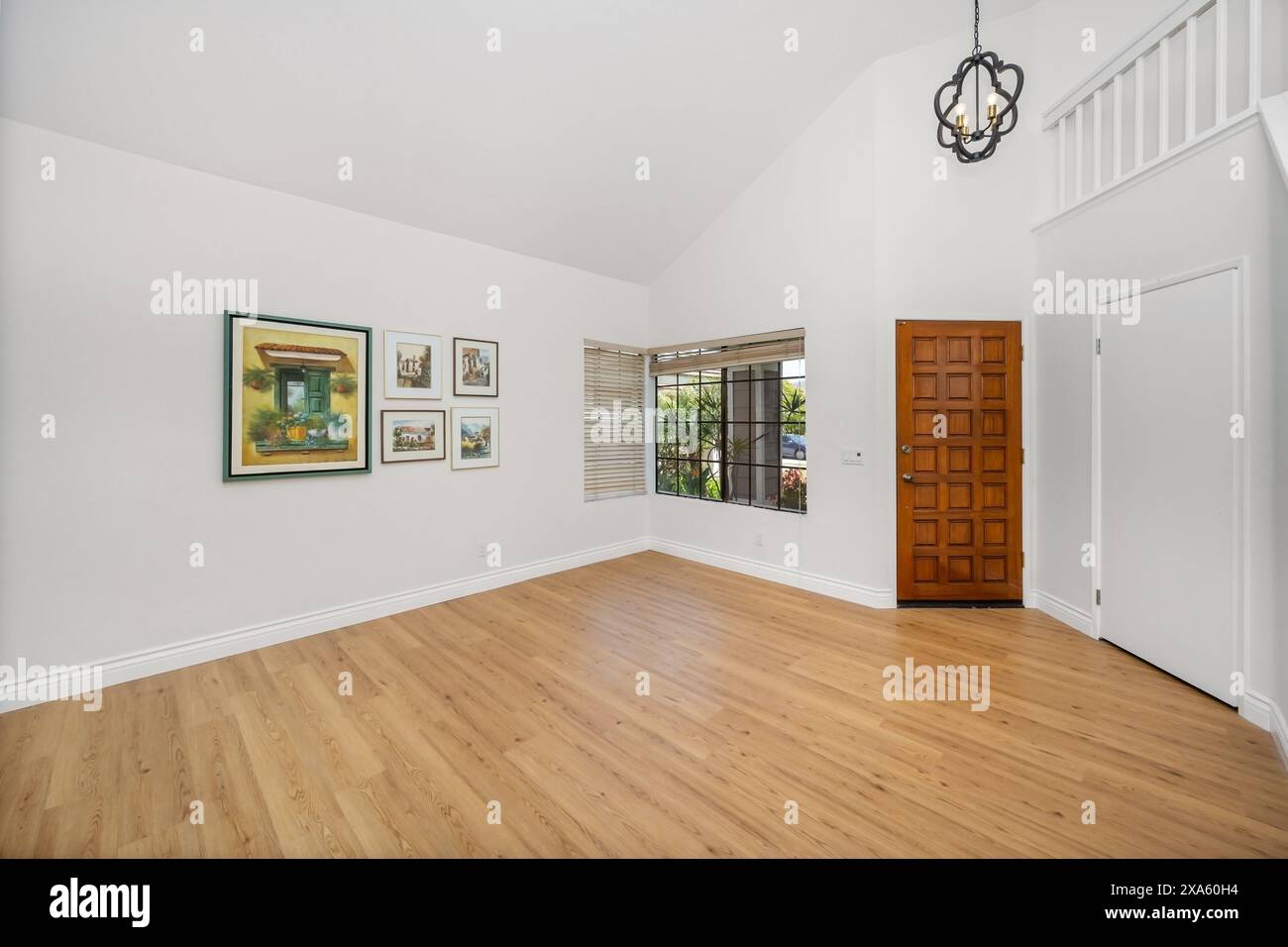 Spacious entry hall with white walls, wooden floors, and artwork on ...