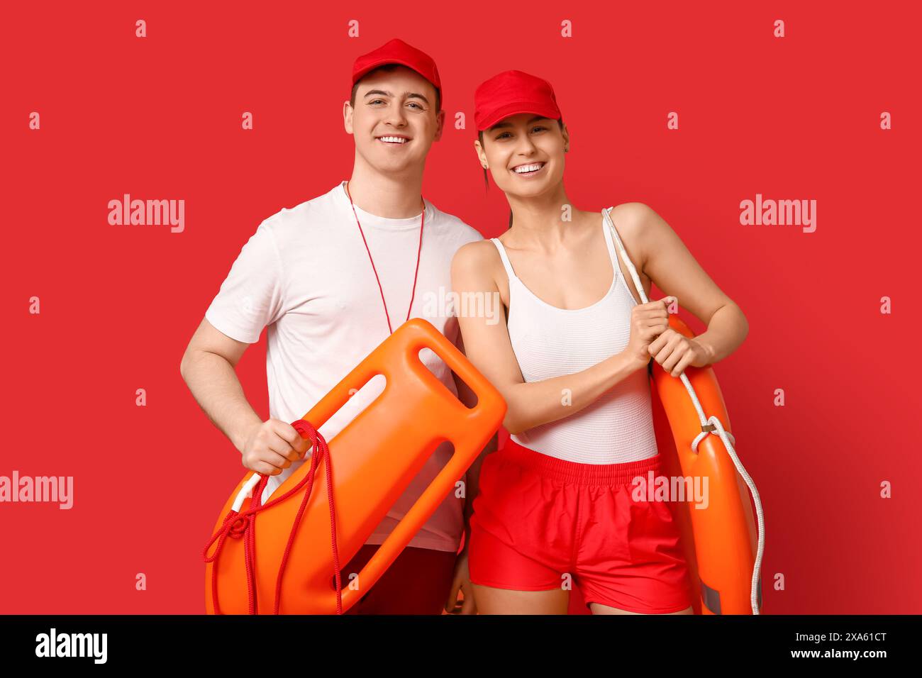 Lifeguards with ring buoy and rescue tube on red background Stock Photo ...