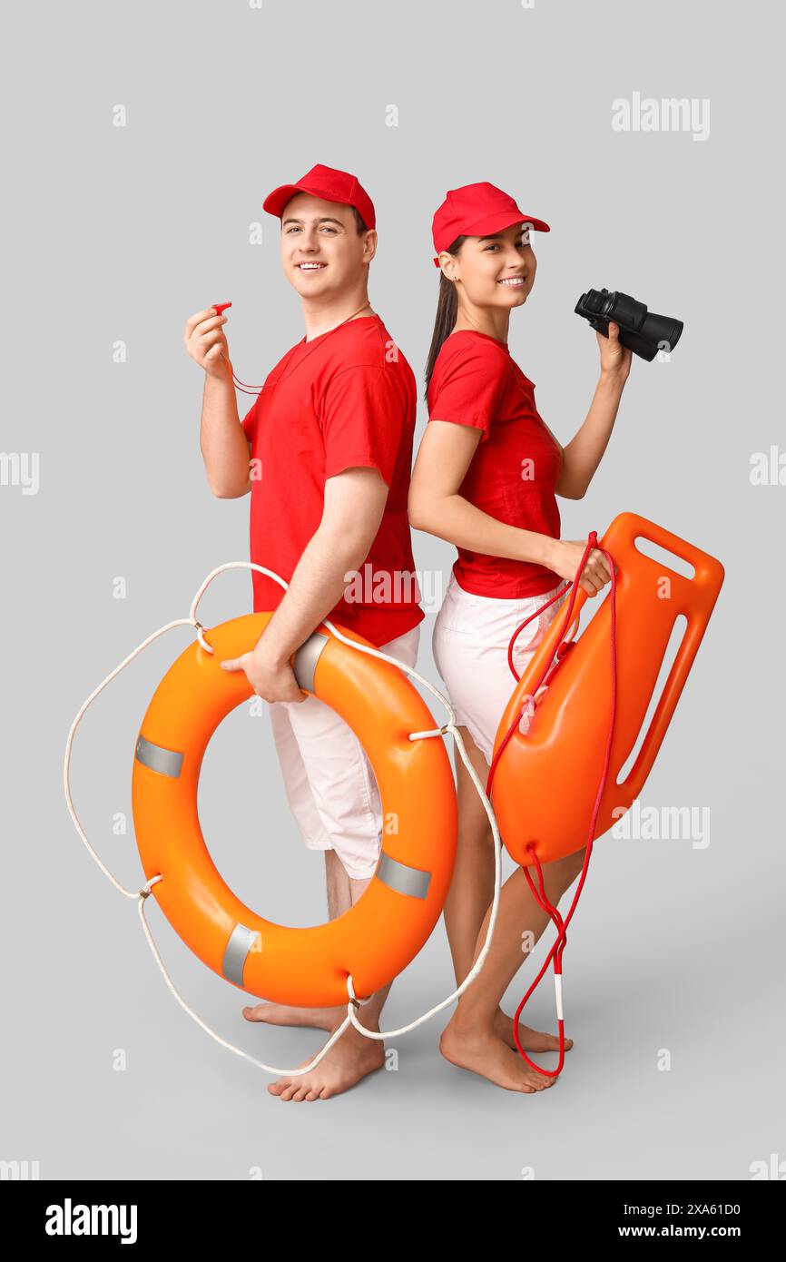 Lifeguards with ring buoy, rescue tube and binoculars on grey ...