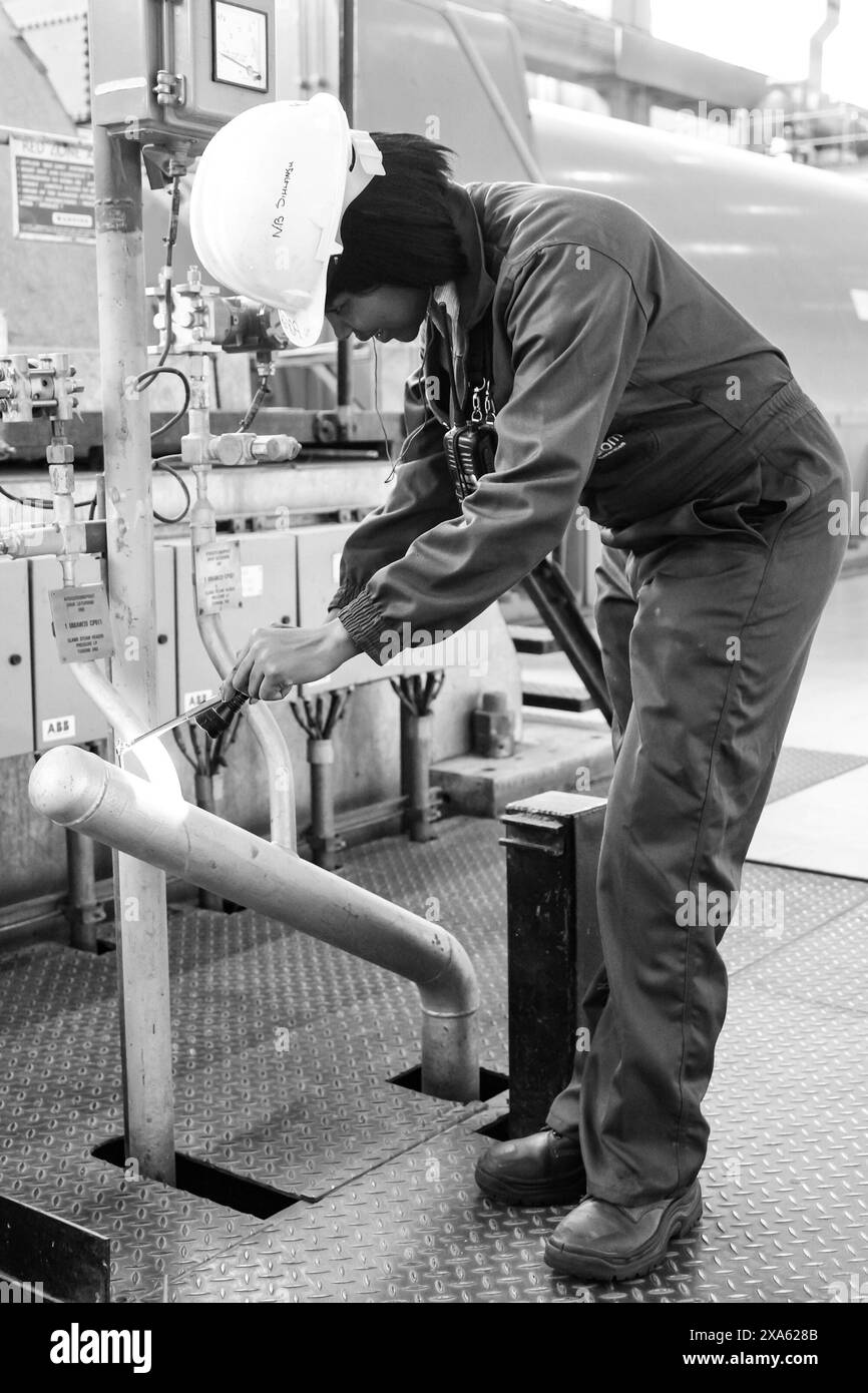 A male engineer in a safety helmet inspecting pipes with a testing ...