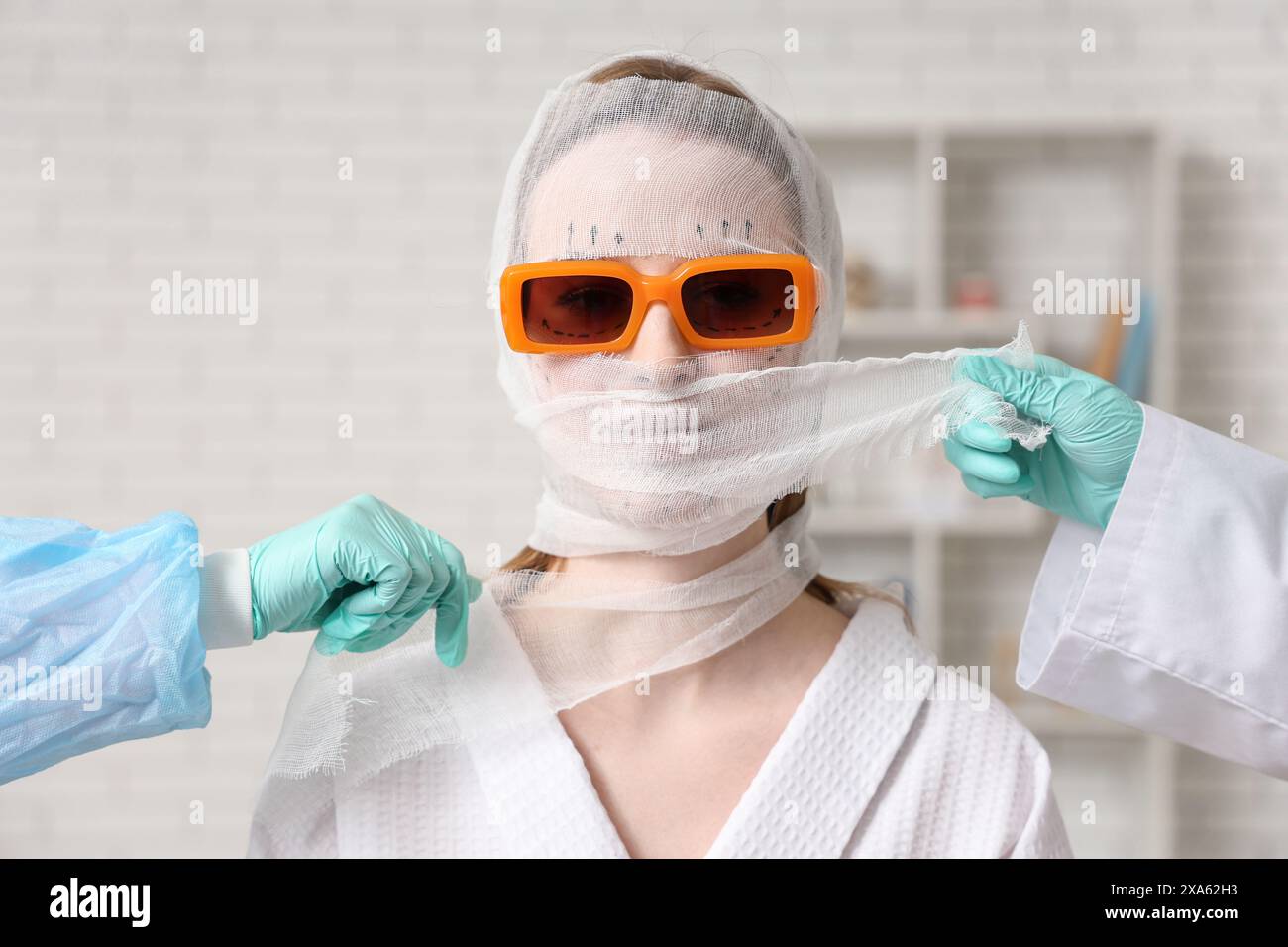Plastic surgeons wrapping gauze around woman's head in clinic, closeup ...