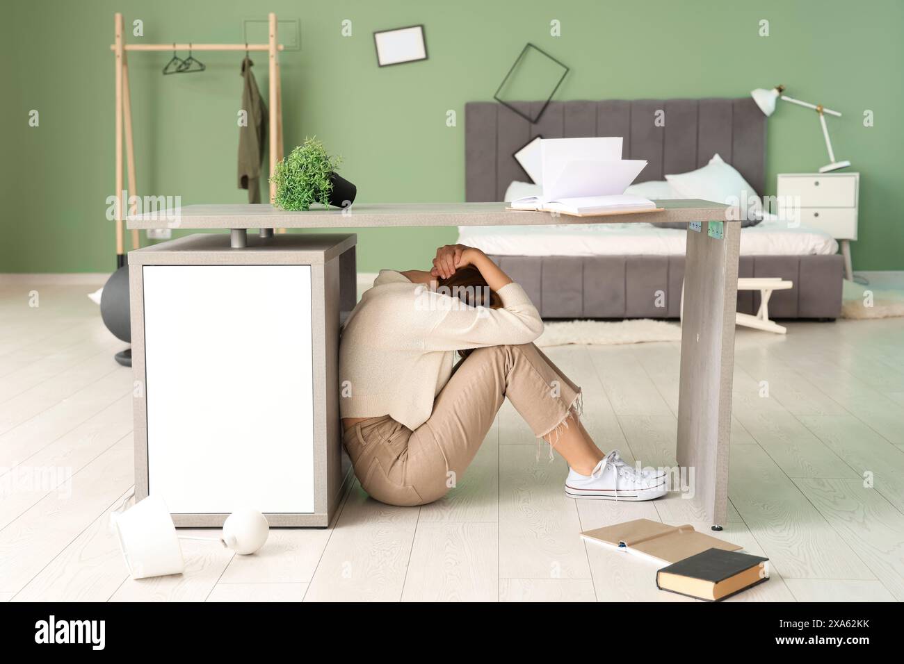 Woman hiding under table during earthquake in bedroom Stock Photo - Alamy