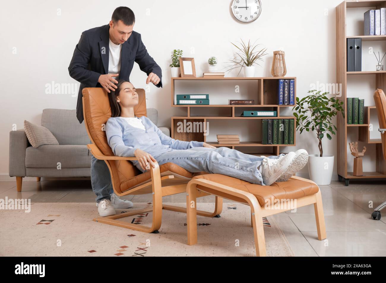 Male psychologist with pendulum hypnotizing young woman in office Stock ...