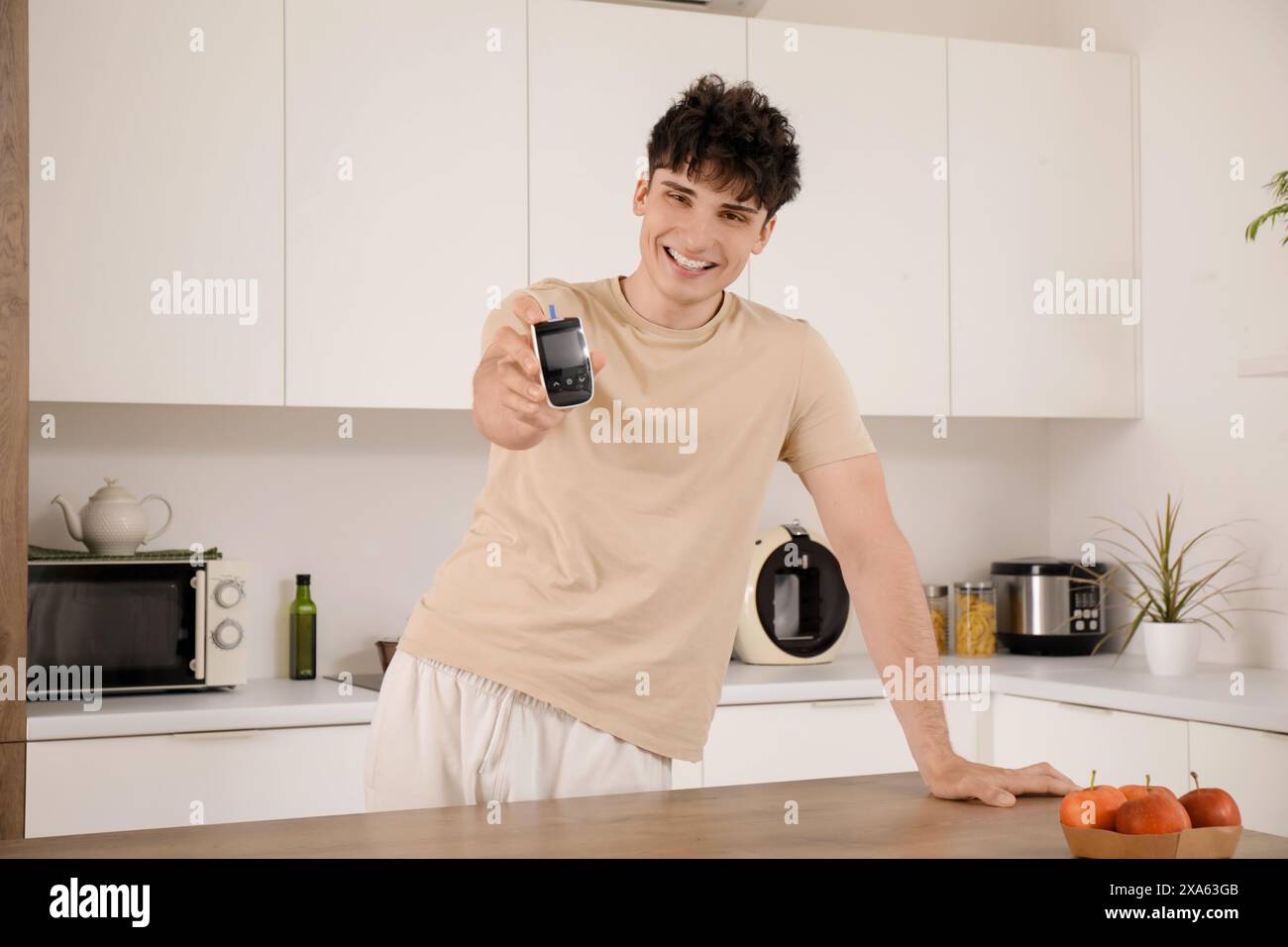 Diabetic young man with glucose sensor and glucometer in kitchen Stock ...