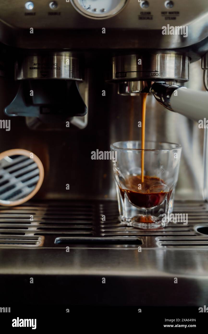 A person pouring freshly brewed coffee from a coffee maker into a cup ...