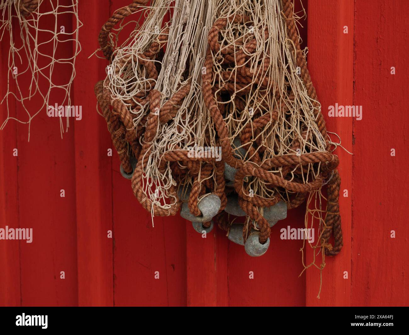 The fishing nets hanging by a red boat on a wall Stock Photo - Alamy