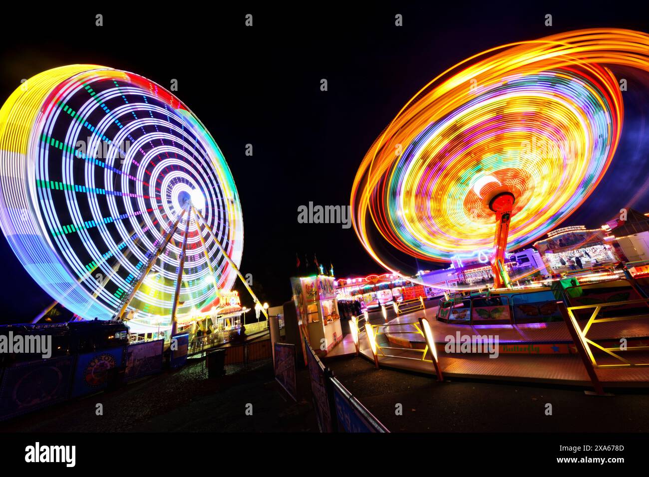 Vibrant fair at night with illuminated ferris wheel Stock Photo - Alamy