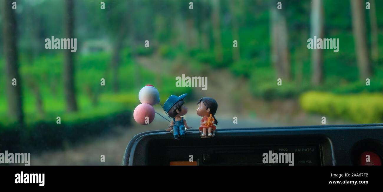 The toy figures with balloons on a car dashboard Stock Photo - Alamy
