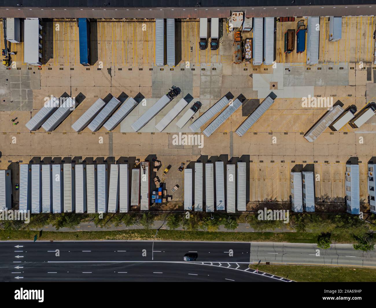 An aerial view of a sunny tractor-trailer parking lot next to a highway ...
