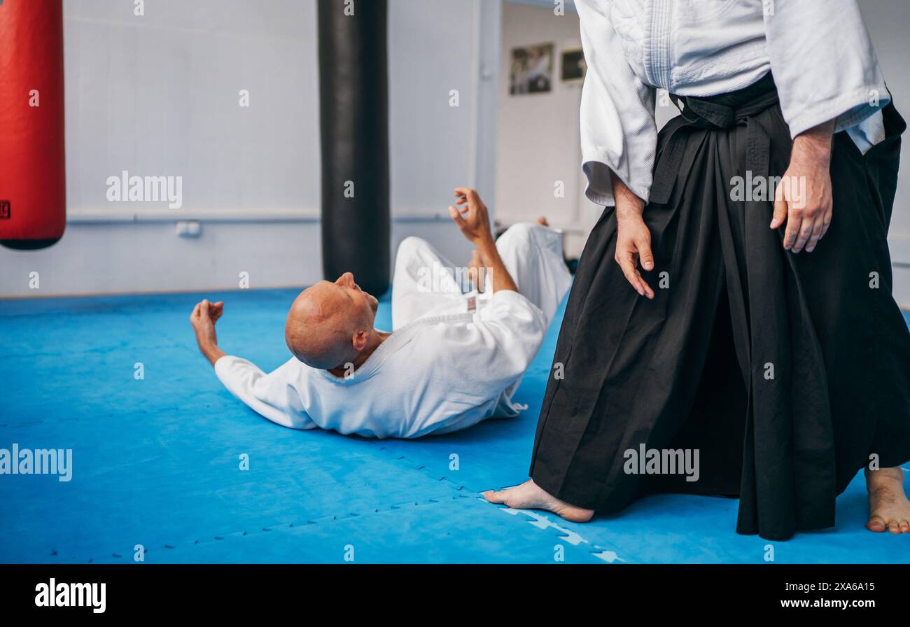 Two men are practicing Aikido in dojo wearing traditional white Kimono ...