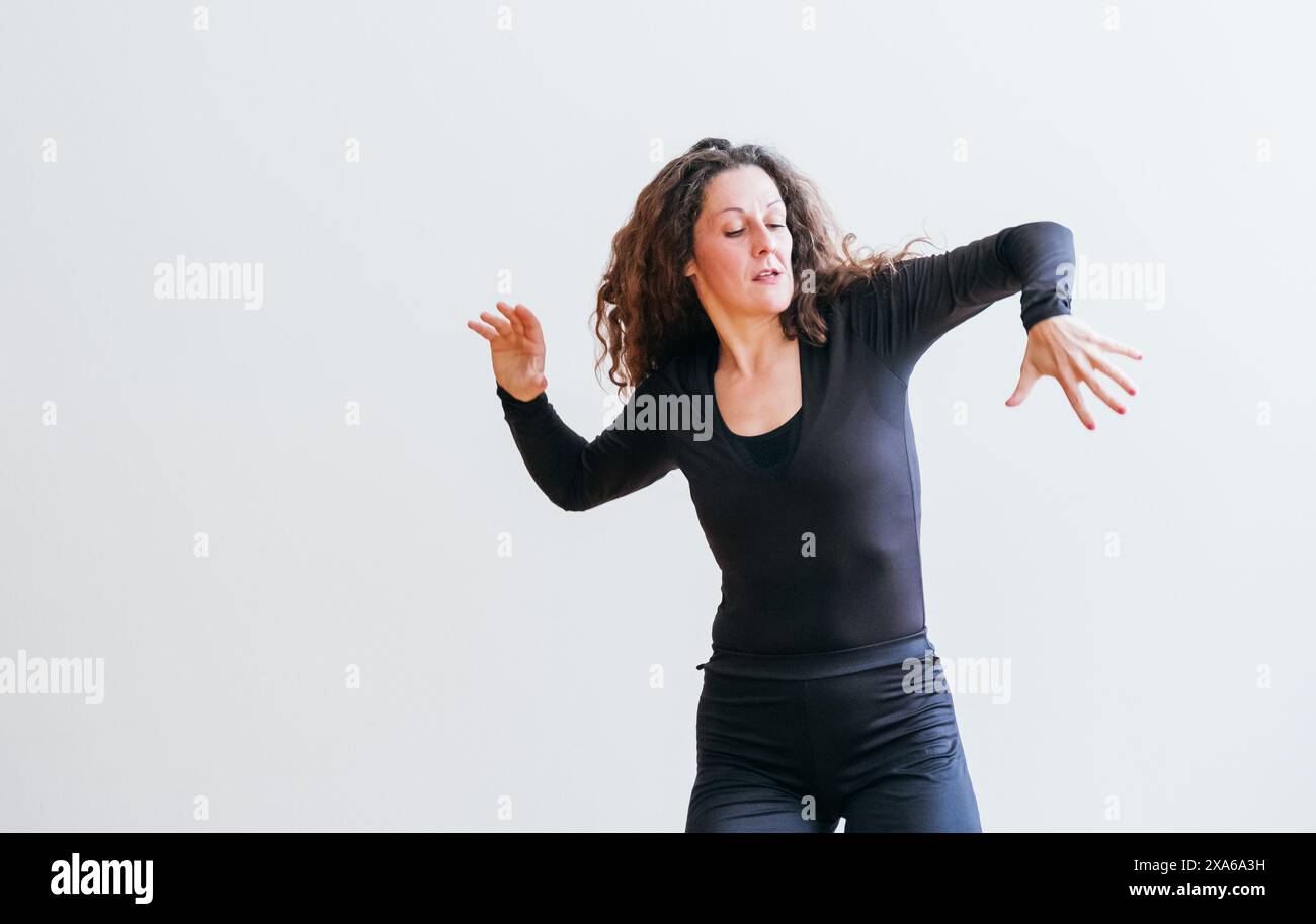 woman in black outfit laughs joyfully while dancing curly hair ...