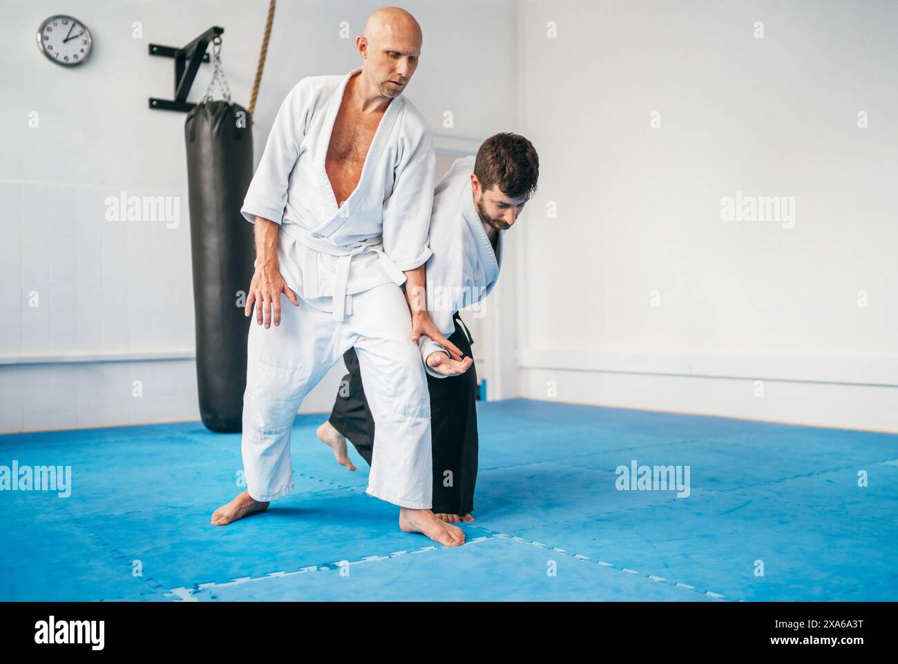 Two men are practicing Aikido in dojo wearing traditional white Kimono ...