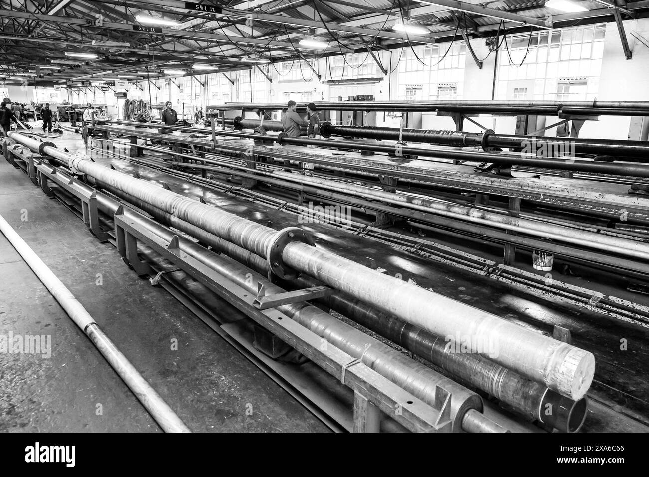 The interior of a factory with machinery manufacturing pipes and rods ...