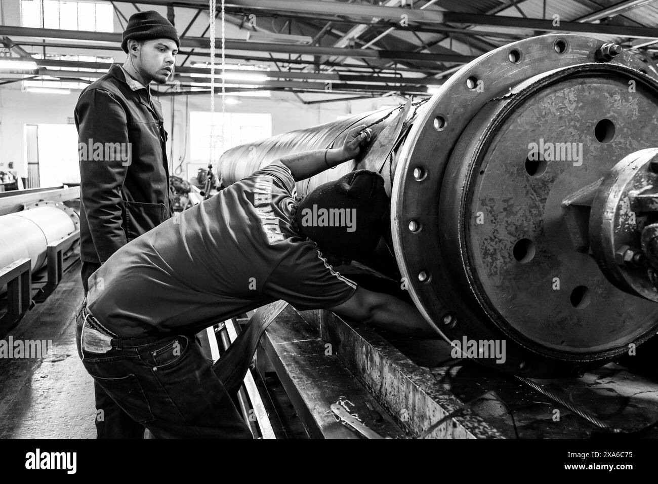 A monochrome image of factory workers operating machinery in ...