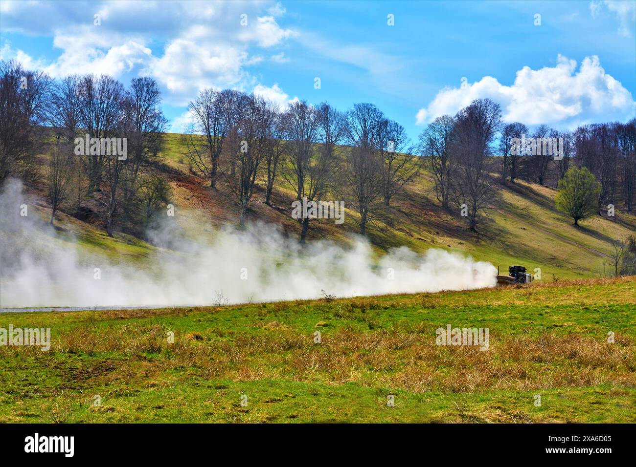 A truck moving on a dirt road raising dust behind it. Dust pollution in ...
