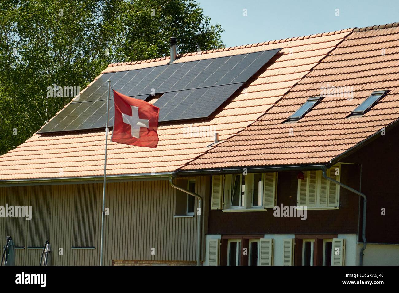 The solar panels on a house roof with a Swiss flag in the foreground ...