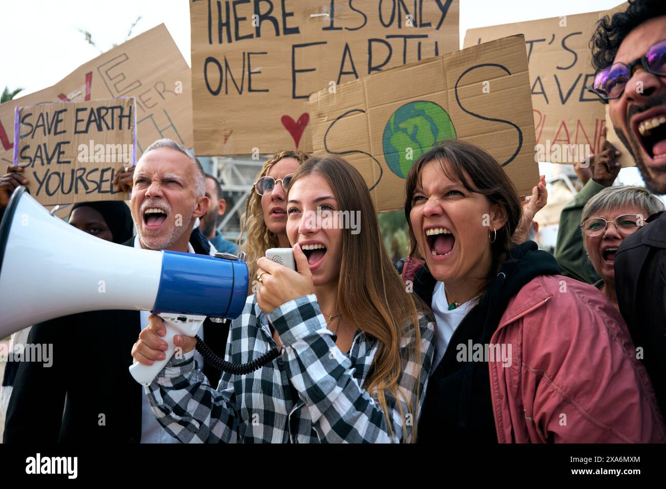 Woman shouting megaphone at protest against pollution of planet. Group ...