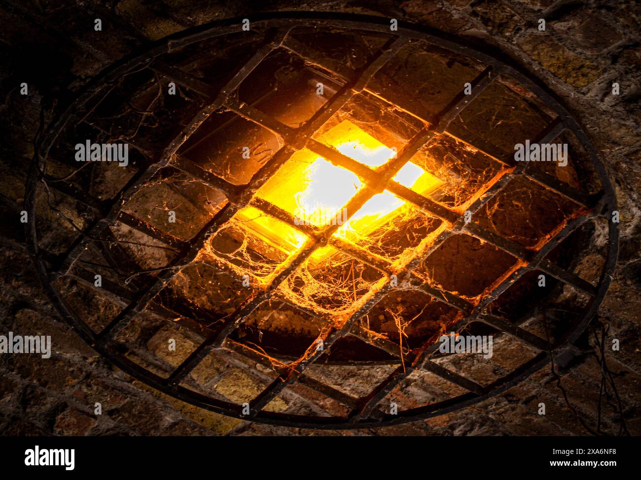 A close-up of light shining through a circular metal fence against a ...