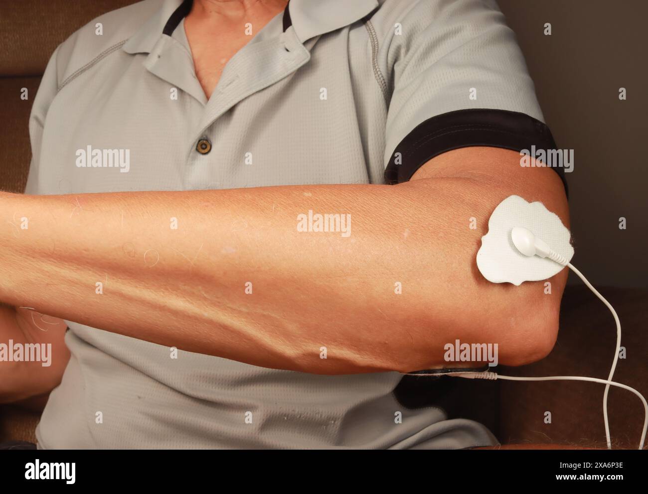 A man using an Electro Therapy Massager or Tens Unit on his elbow Stock ...