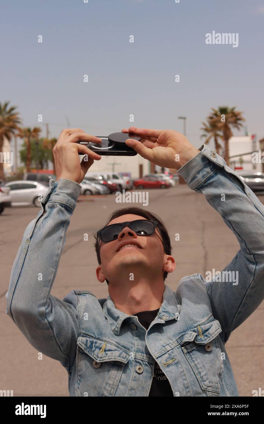 A young man looking at the sun and taking photos during a solar eclipse ...