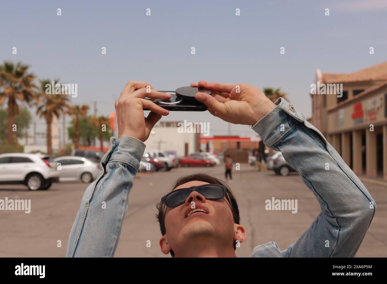 A young man looking at the sun and taking photos during a solar eclipse ...