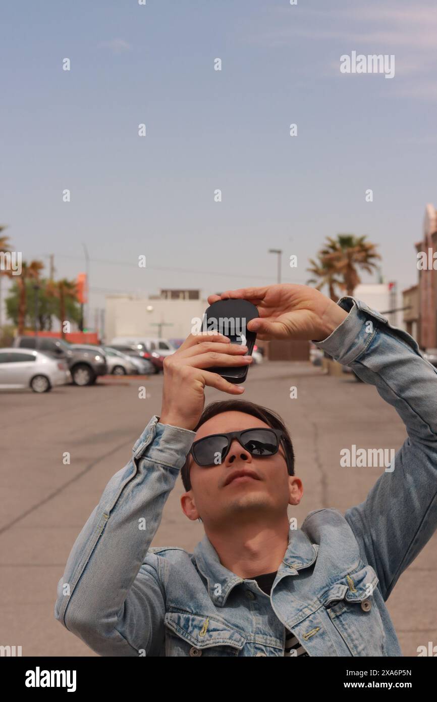 A young man looking at the sun and taking photos during a solar eclipse ...