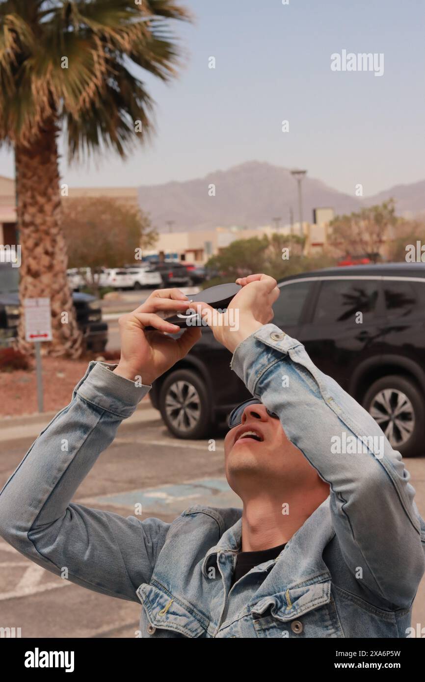 A young man looking at the sun and taking photos during a solar eclipse ...