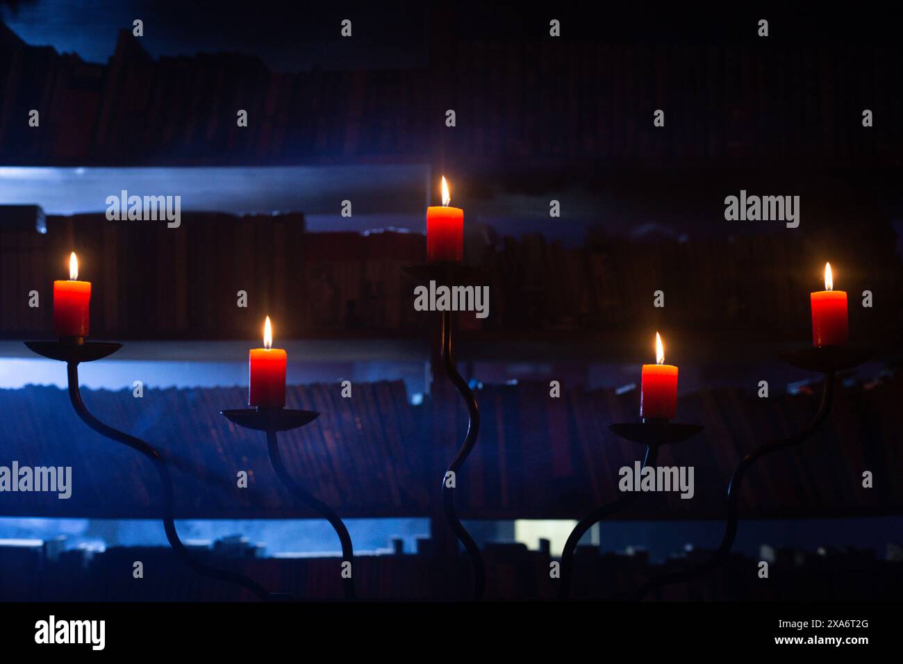 Five lit candles on an open shelf in a dark setting Stock Photo - Alamy