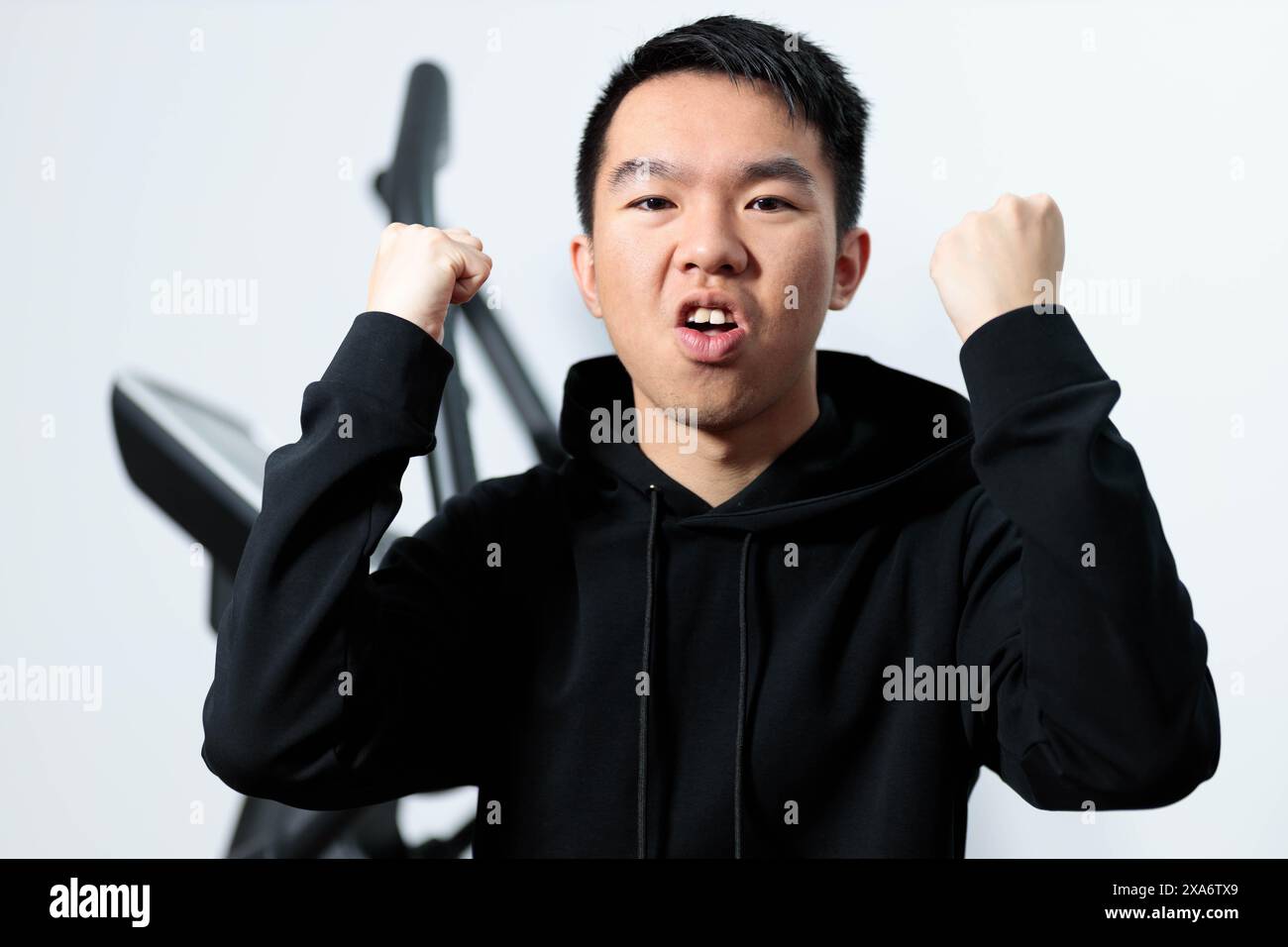 A happy young man raising his fists in triumph, wearing black hoodie ...