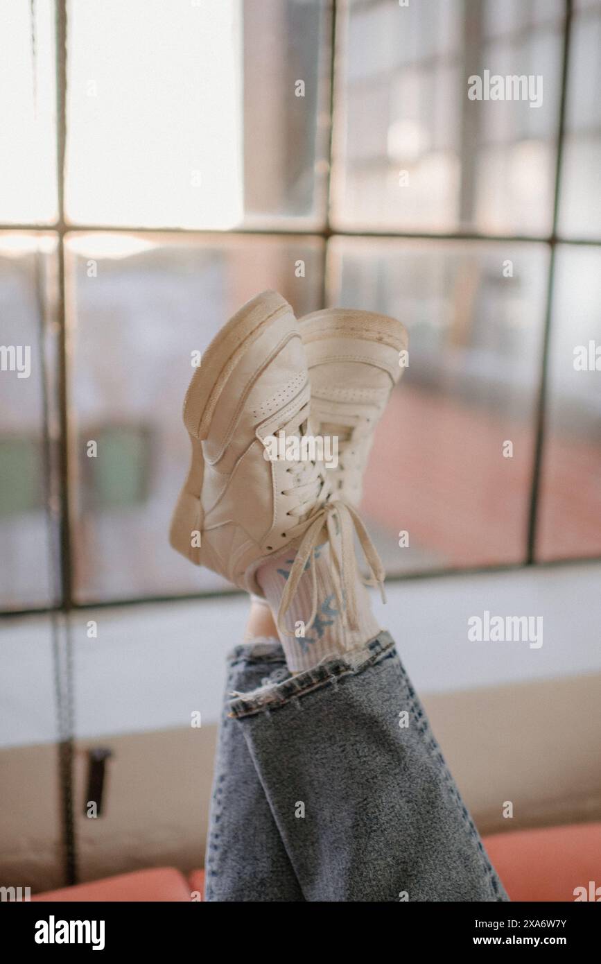Person in jeans and sneakers lifting leg to window Stock Photo - Alamy