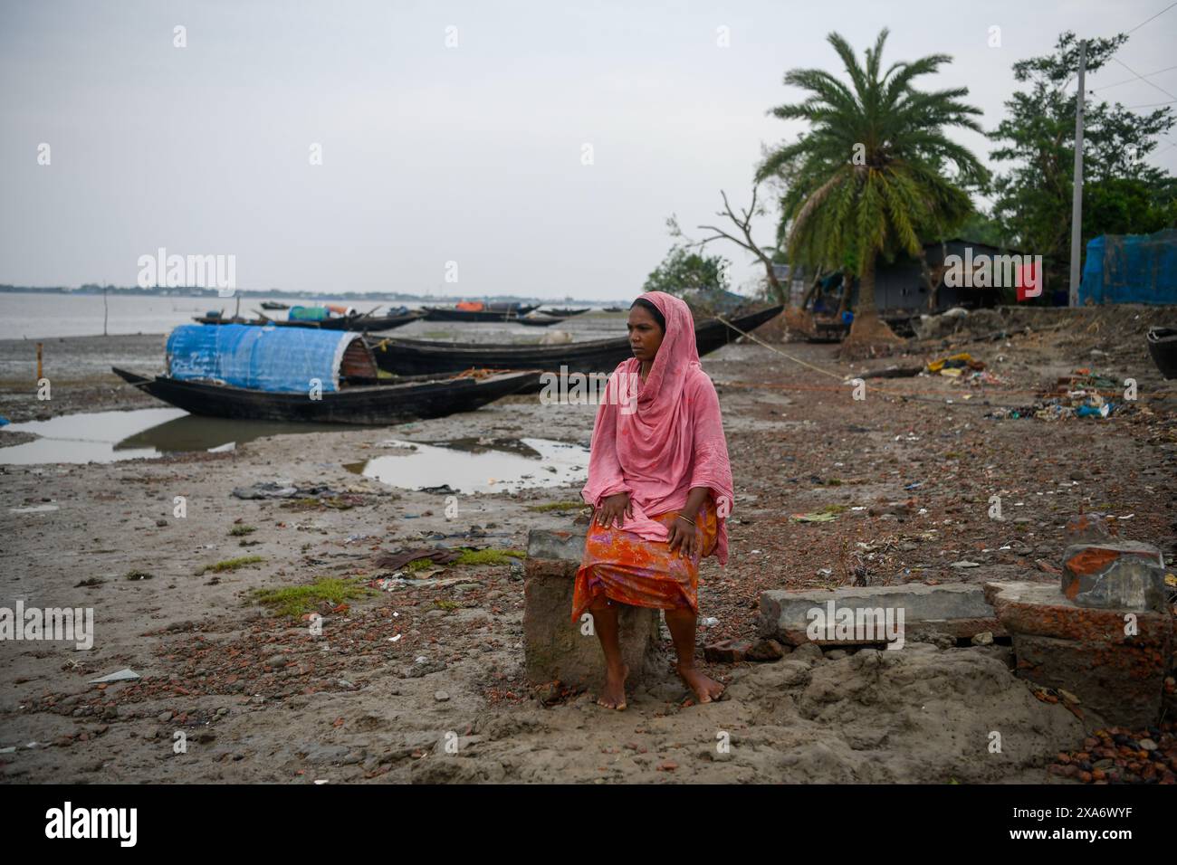 A woman sits on the ruins of the damaged house during the aftermath in ...