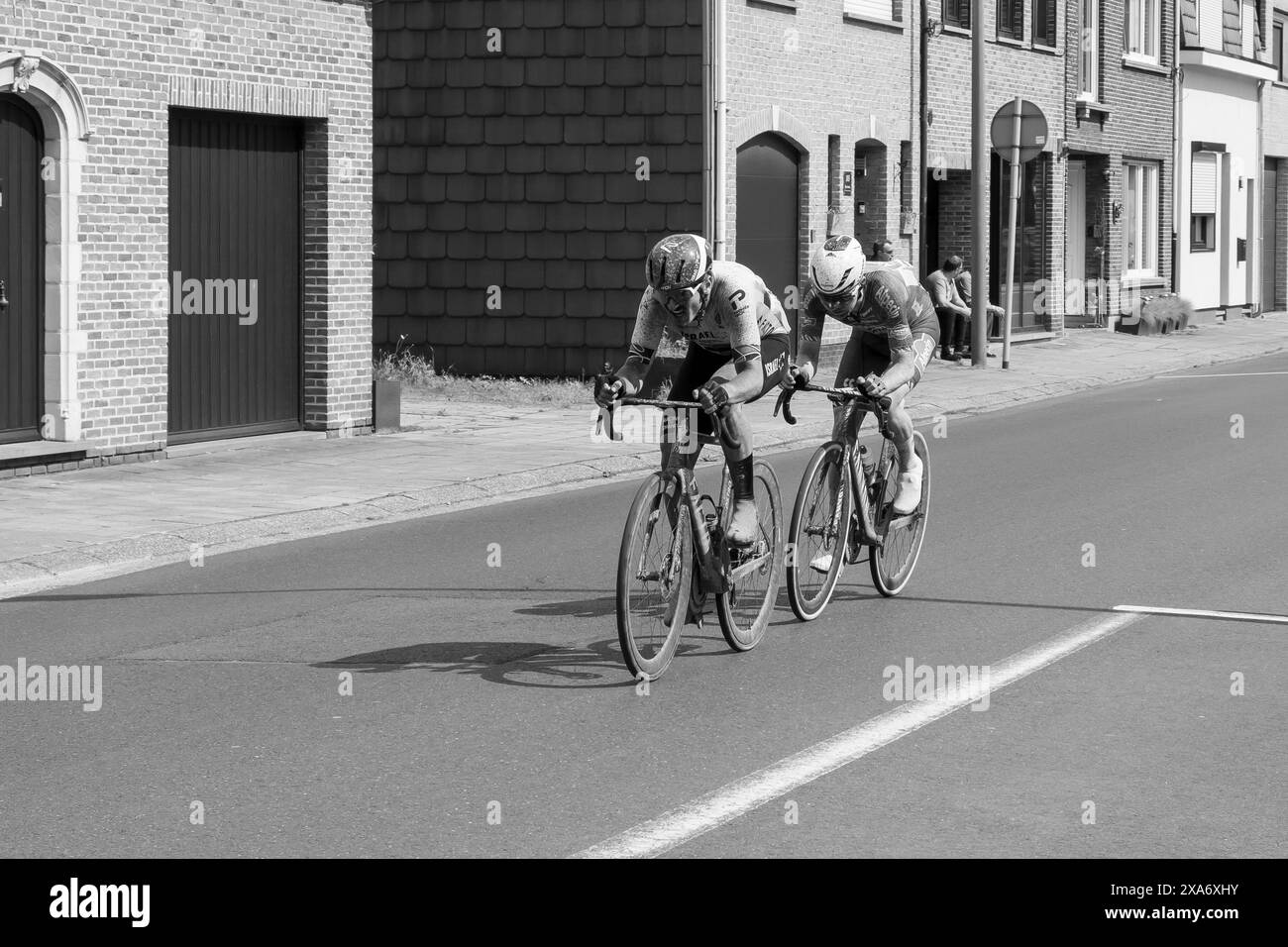 Two cyclists biking in a quaint neighborhood with small buildings Stock ...