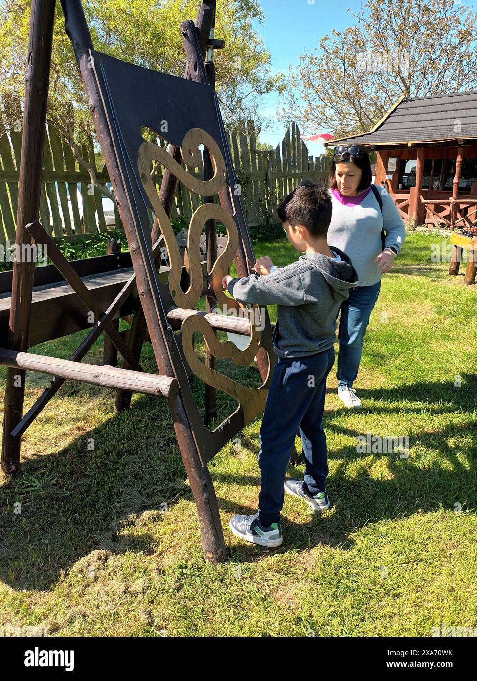 A boy playing with a large wooden object next to a woman Stock Photo ...