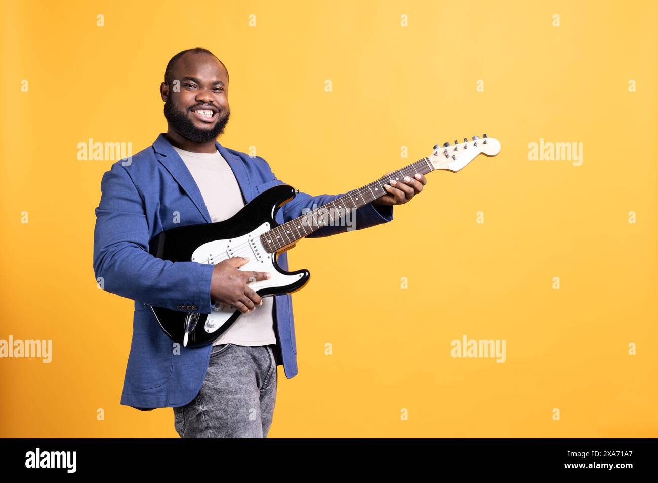 Portrait of happy man holding guitar, performing rock tunes during ...