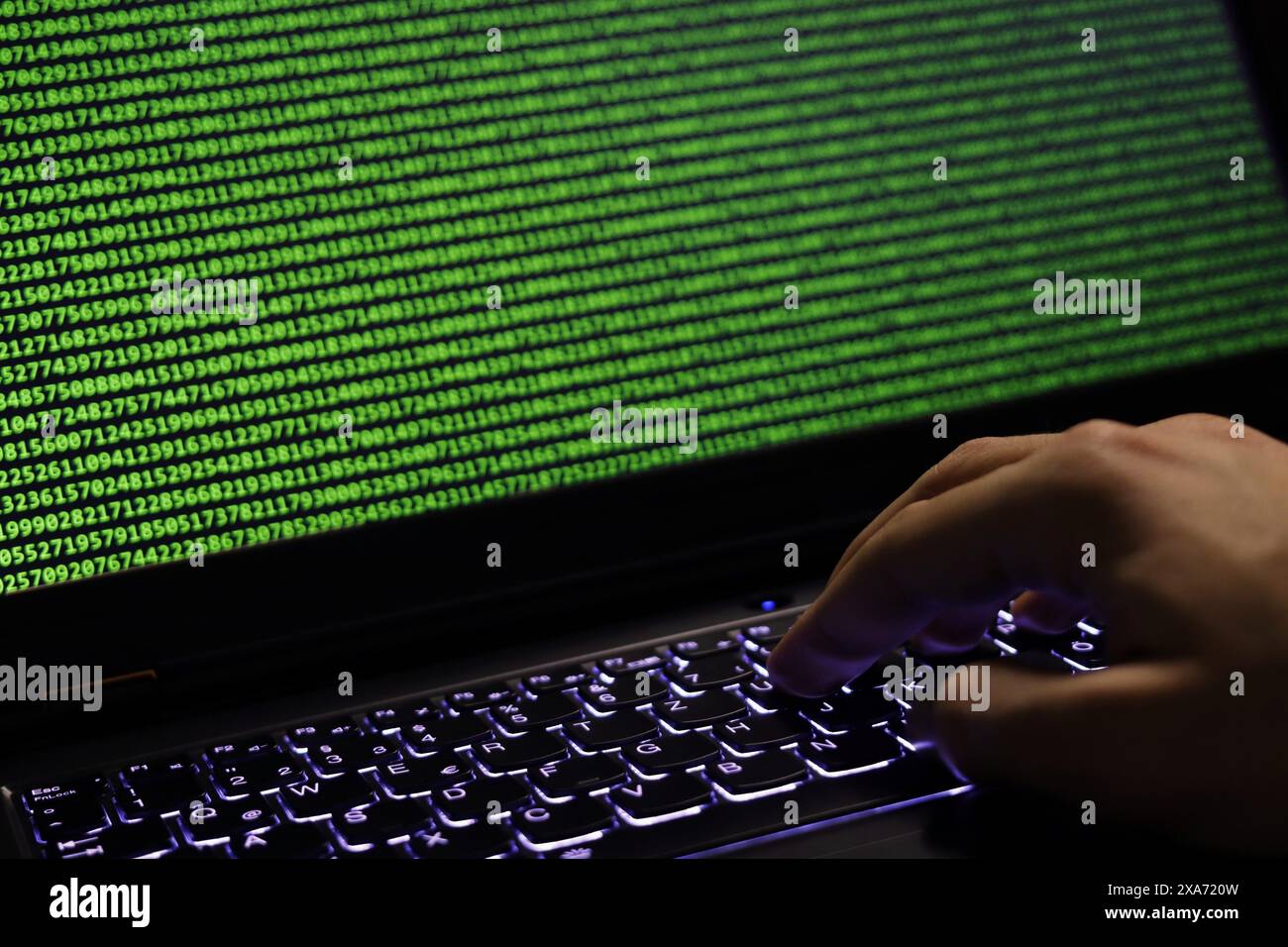 A man is illuminated by the glow of his computer screen as he types on ...
