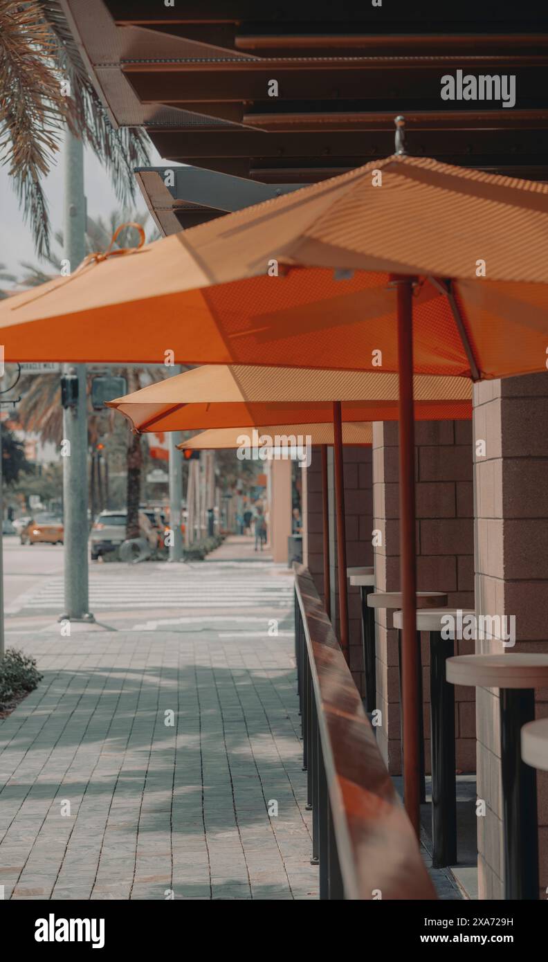 An outdoor patio with multiple tables and umbrellas next to a brick ...
