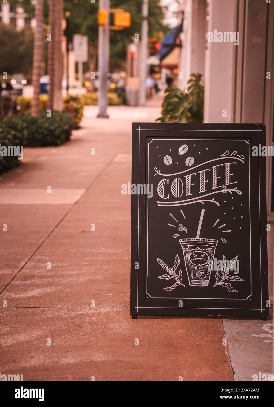 A coffee sign on a sidewalk near bushes Stock Photo - Alamy
