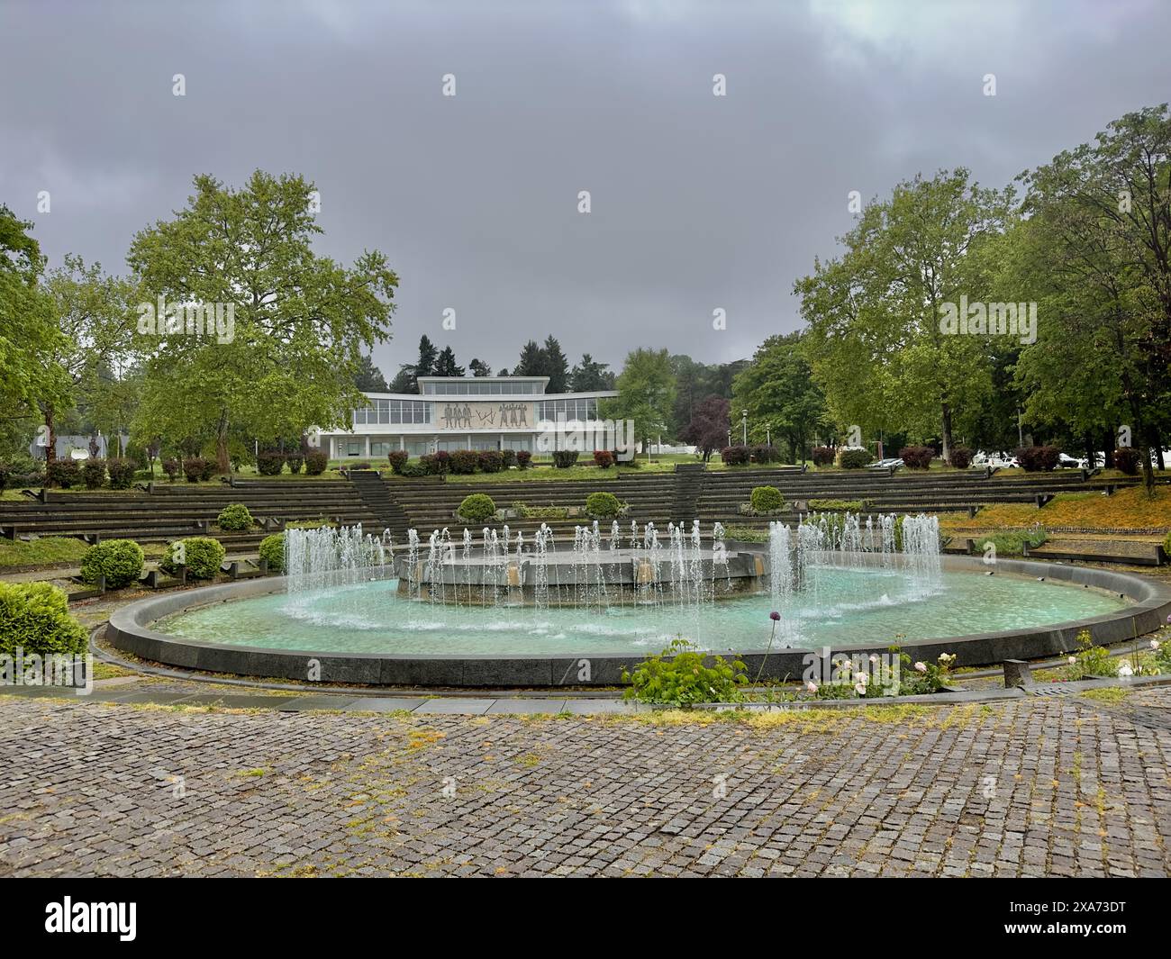 A fountain surrounded by lush greenery and architecture, filled with ...